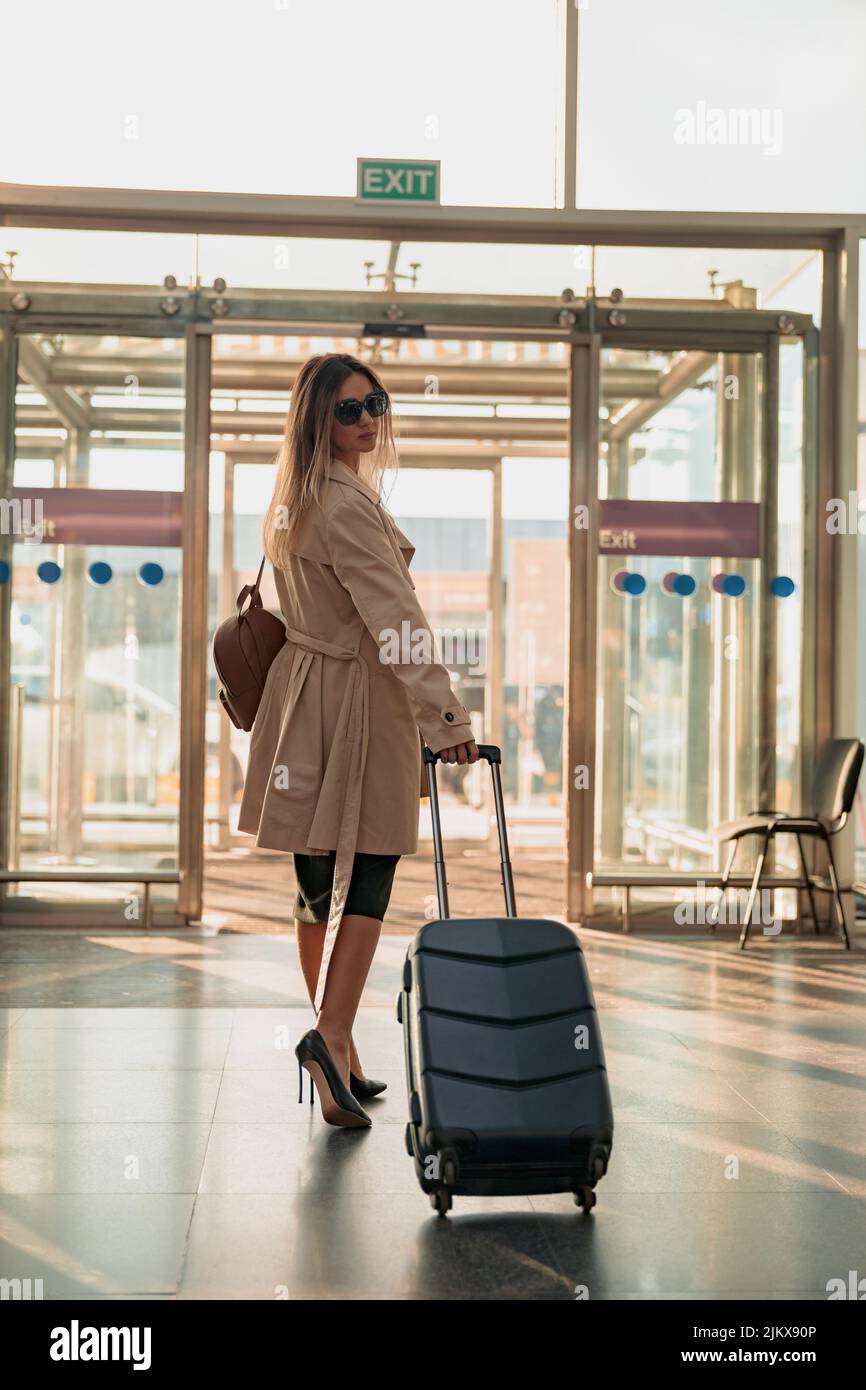 Young pretty lady with suitcase and backpack at the airport Stock Photo ...