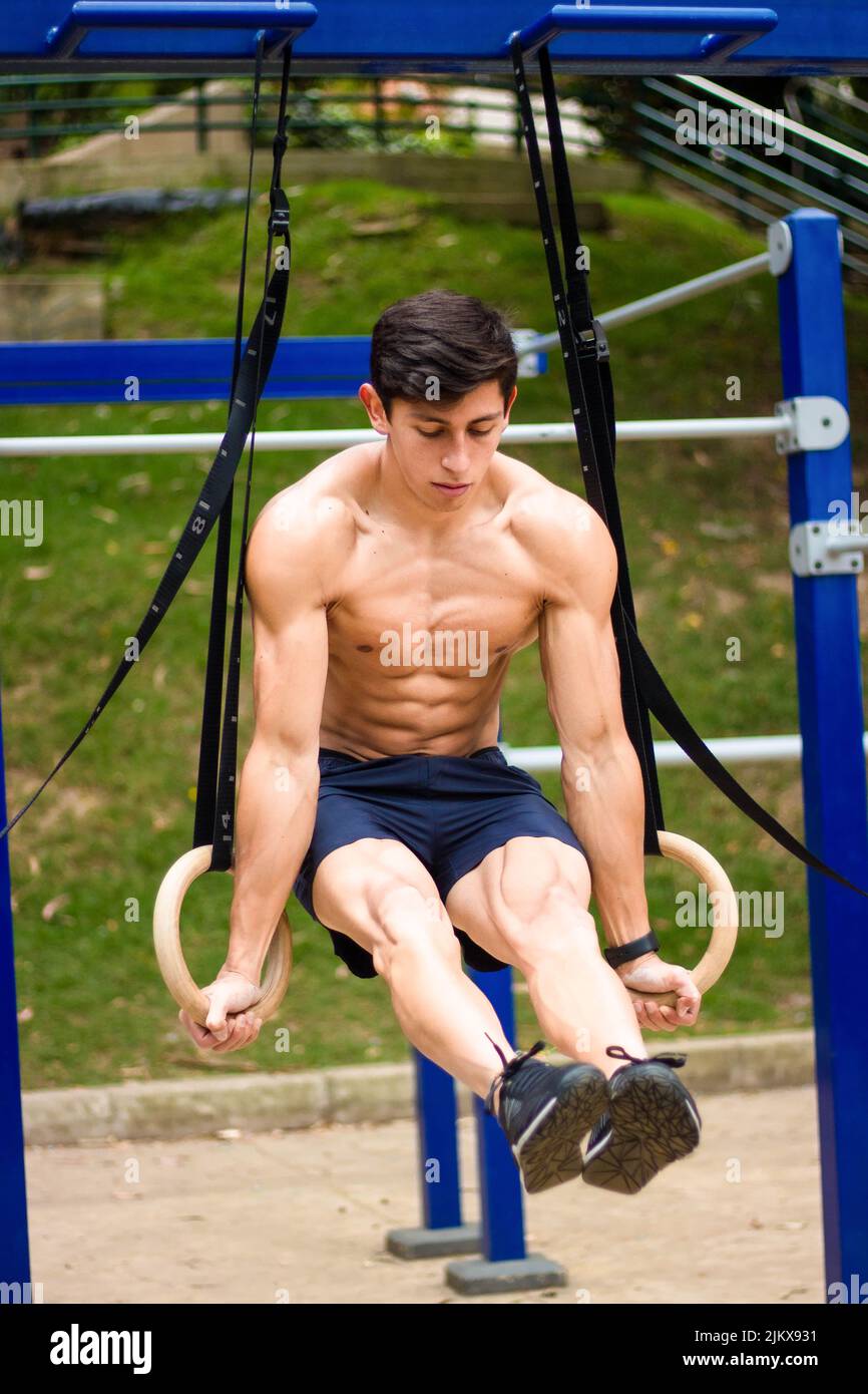 A vertical closeup of a Hispanic male athlete doing gymnastics outdoors ...