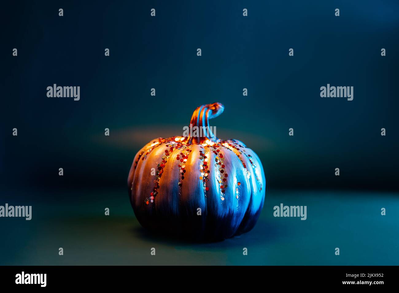 Decorative pumpkin with sparkles in neon warm orange and blue light on ...