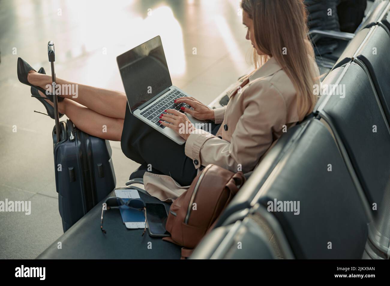 Woman typing on laptop while putting her feet on the suitcase in the ...