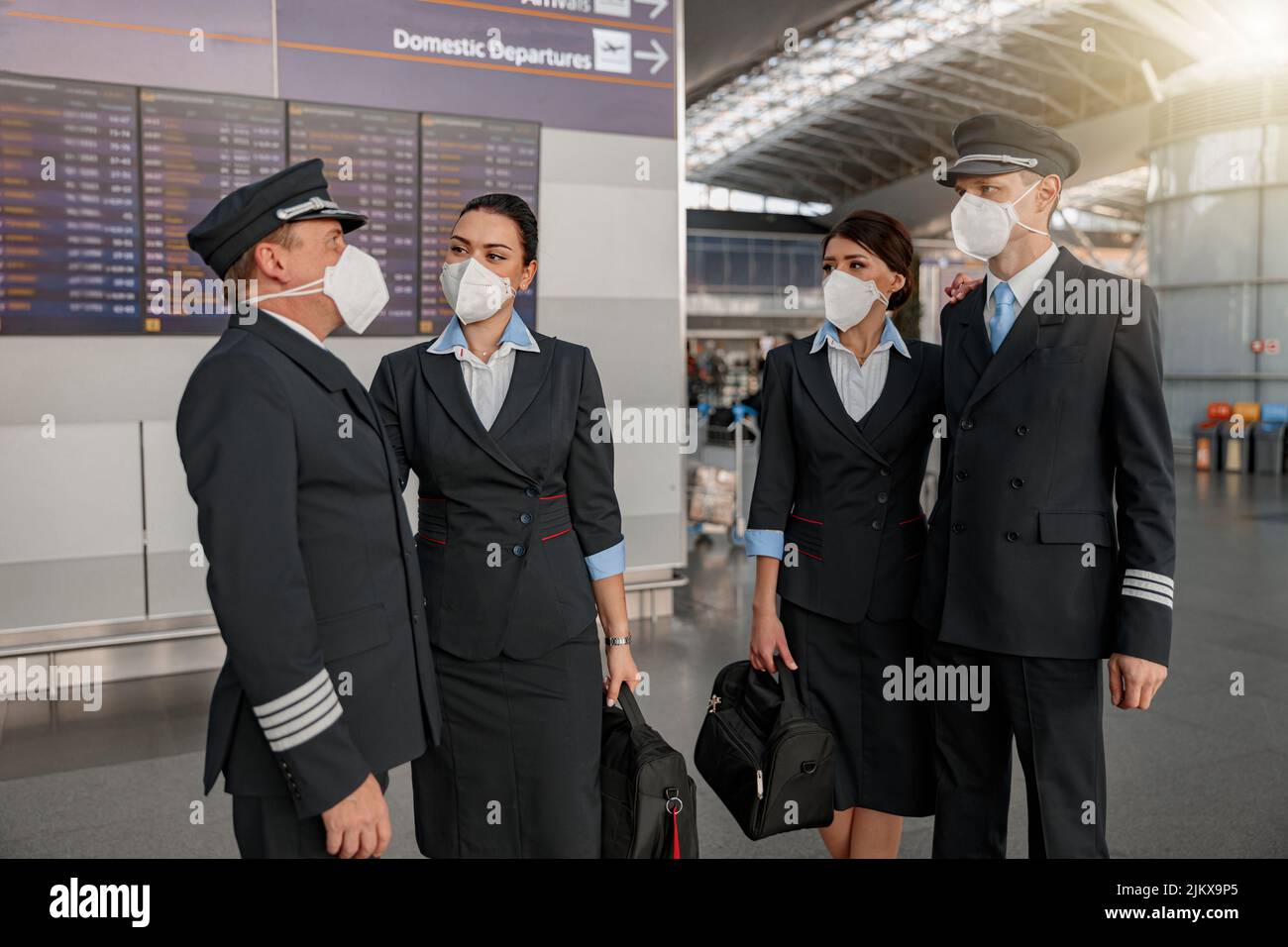 Flight team standing together in airport terminal while talking Stock ...