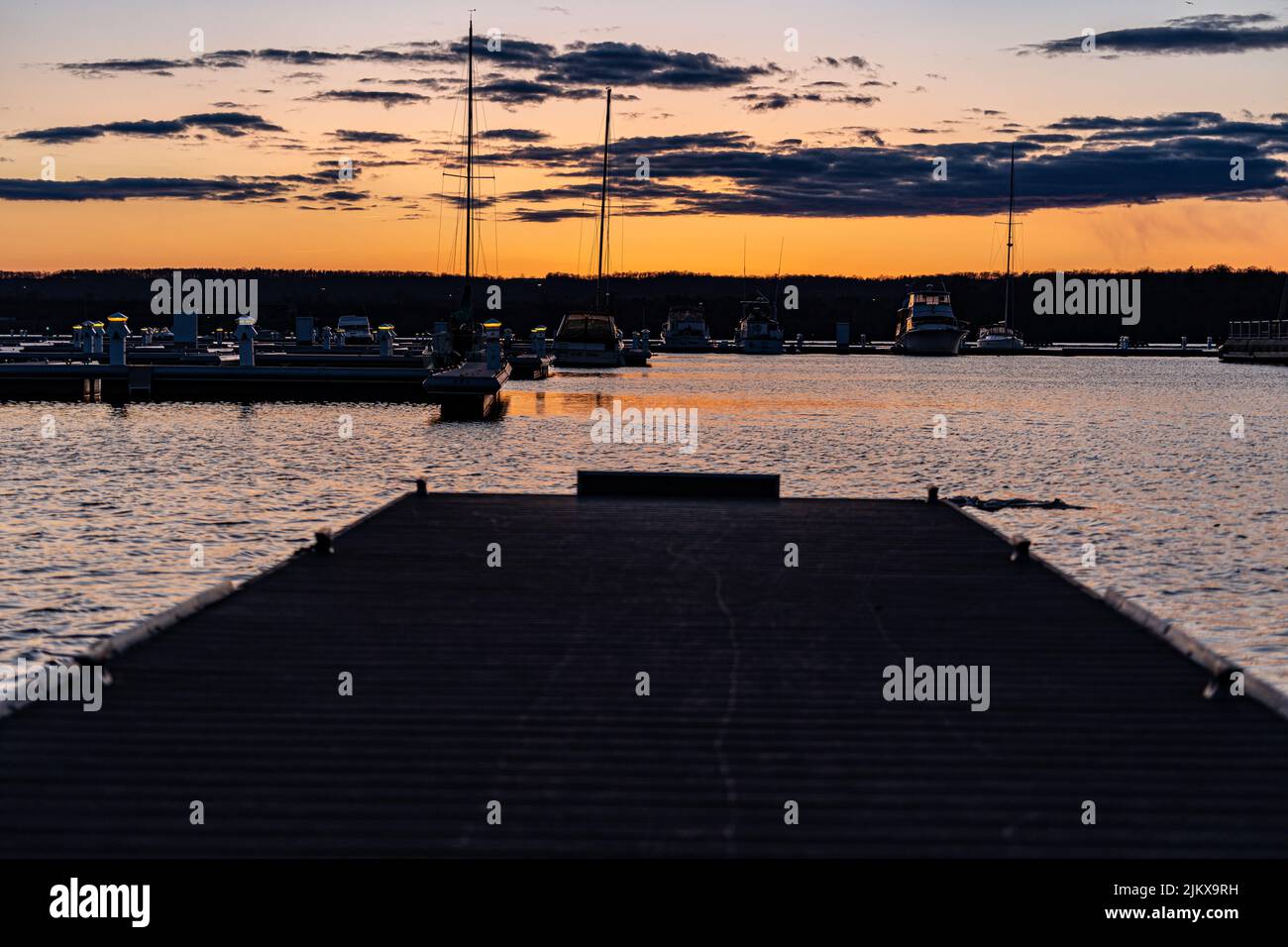 A sunset view on the lake deck with ships floating and a cloudy day ...