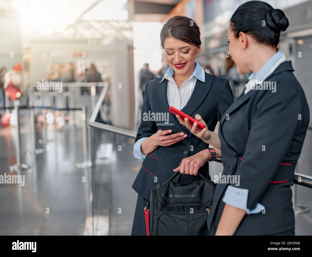 Two beautiful stewardesses using phones and waiting for the flight ...