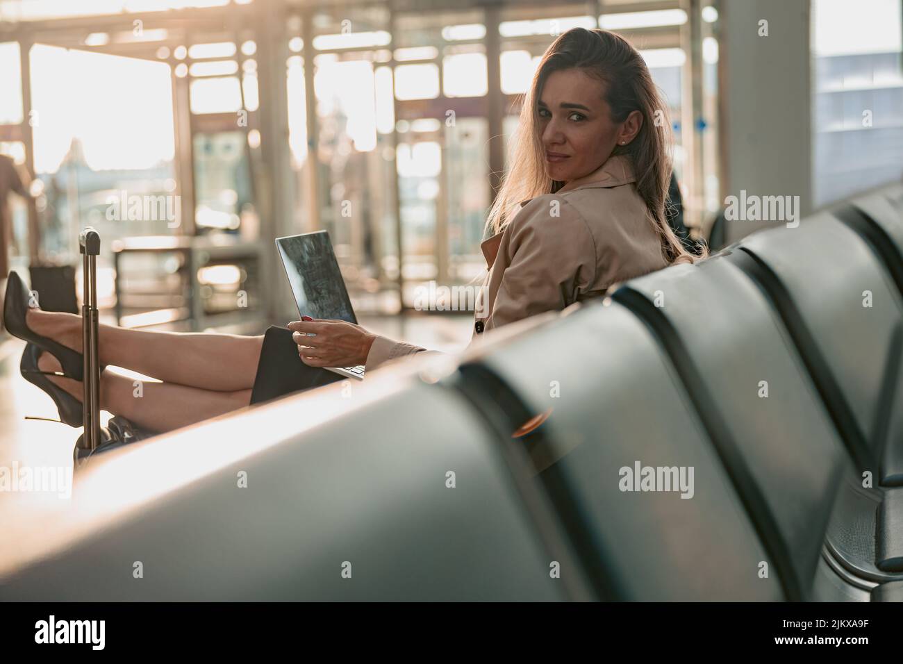 Beautiful woman working with laptop while putting her feet on the ...