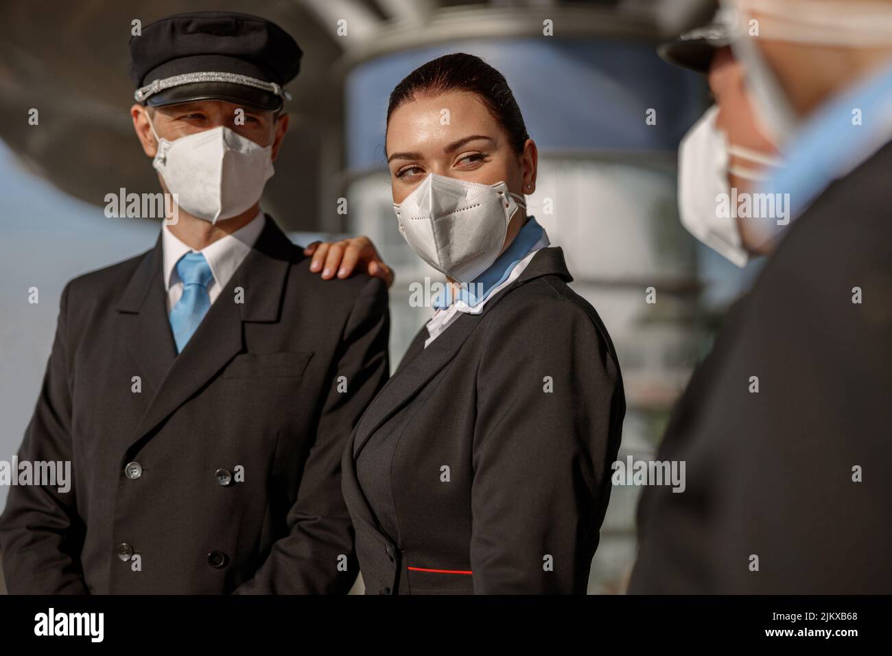 Pilot and stewardess in masks looking at their colleagues Stock Photo ...