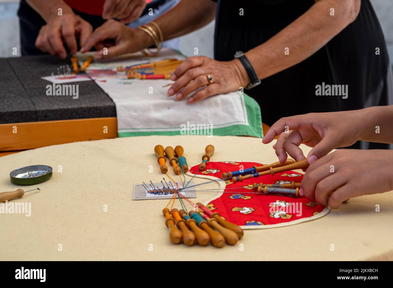 Hands of child and adult making bobbin lace. Colorful lace threads ...