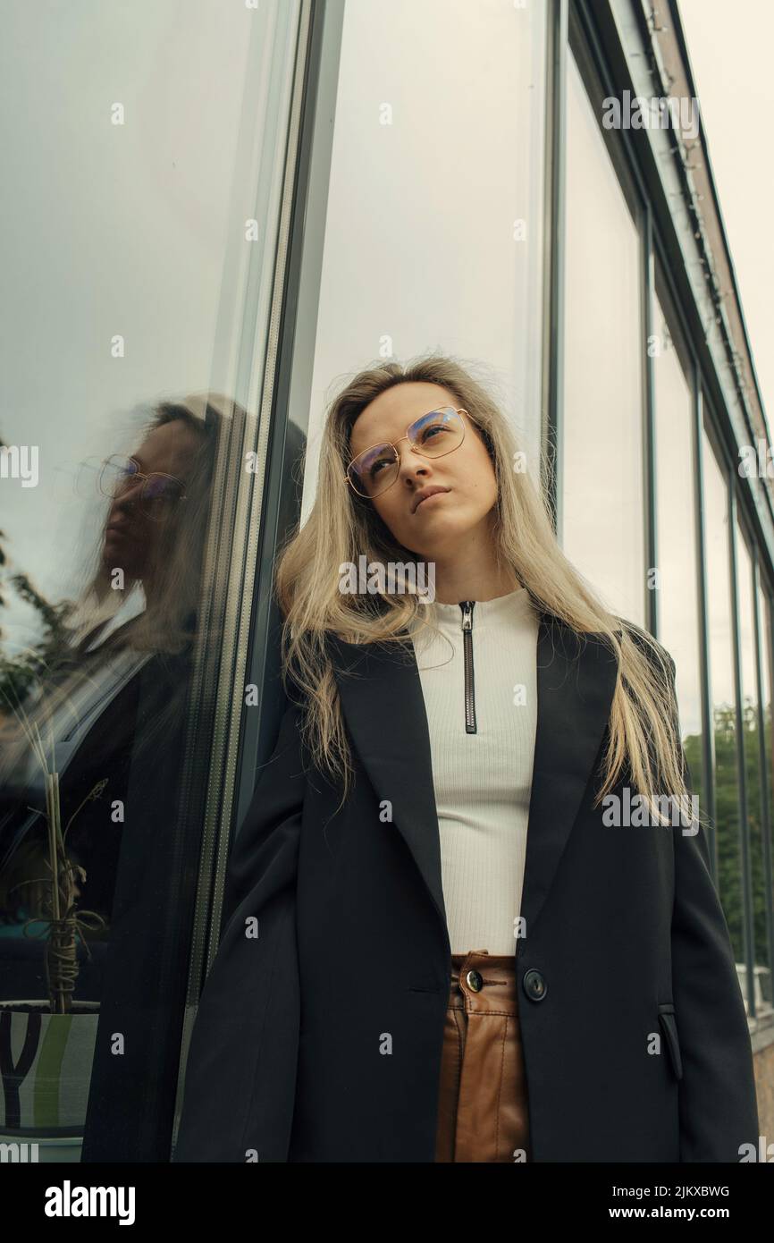 A beautiful woman stands leaning against the window of a building ...