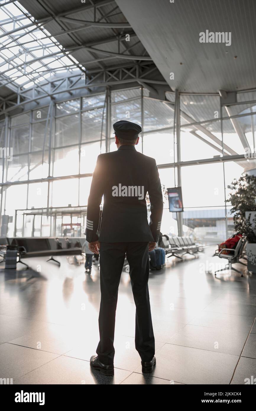 Adult male pilot in uniform standing in airport terminal Stock Photo ...