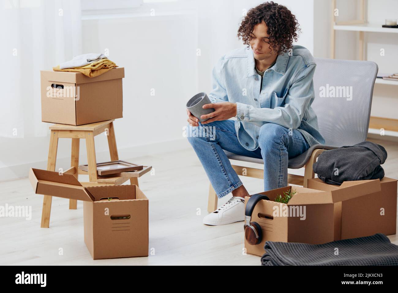 A young man unpacking things from boxes in the room sorting things out ...