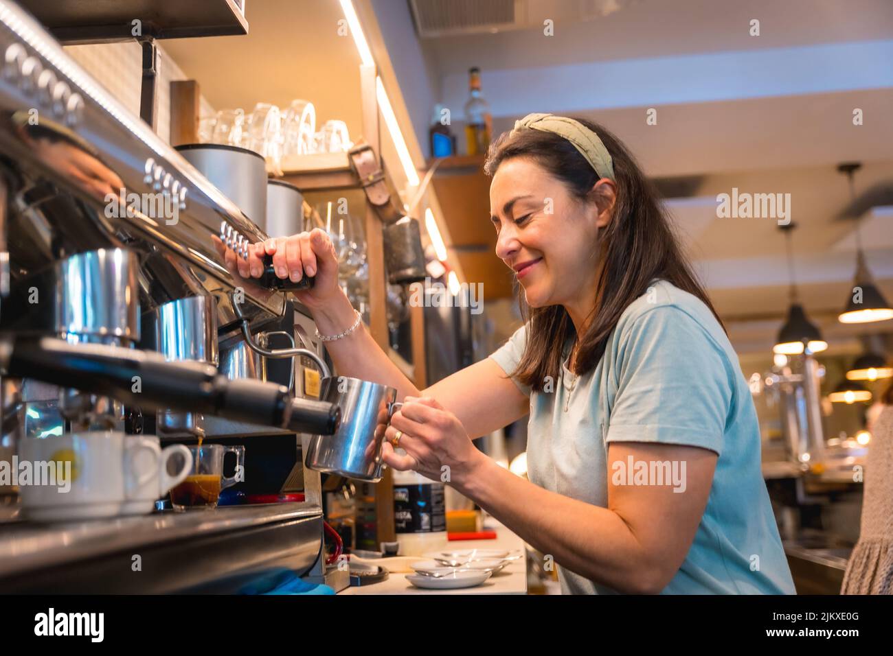 Smiling waitress in female cafeteria preparing coffee in a coffee ...