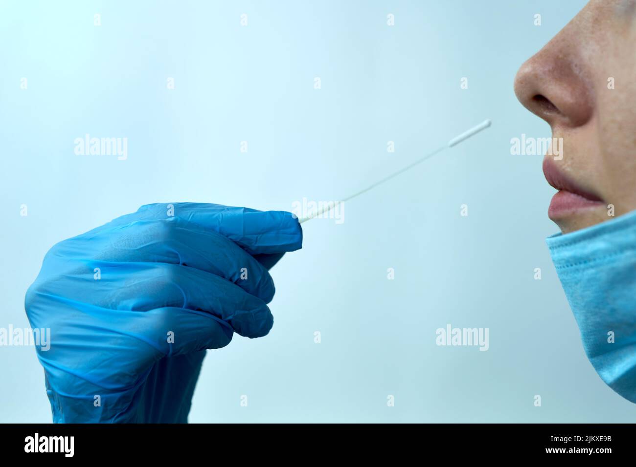 Doctor taking a virus test sample to female patient Stock Photo - Alamy