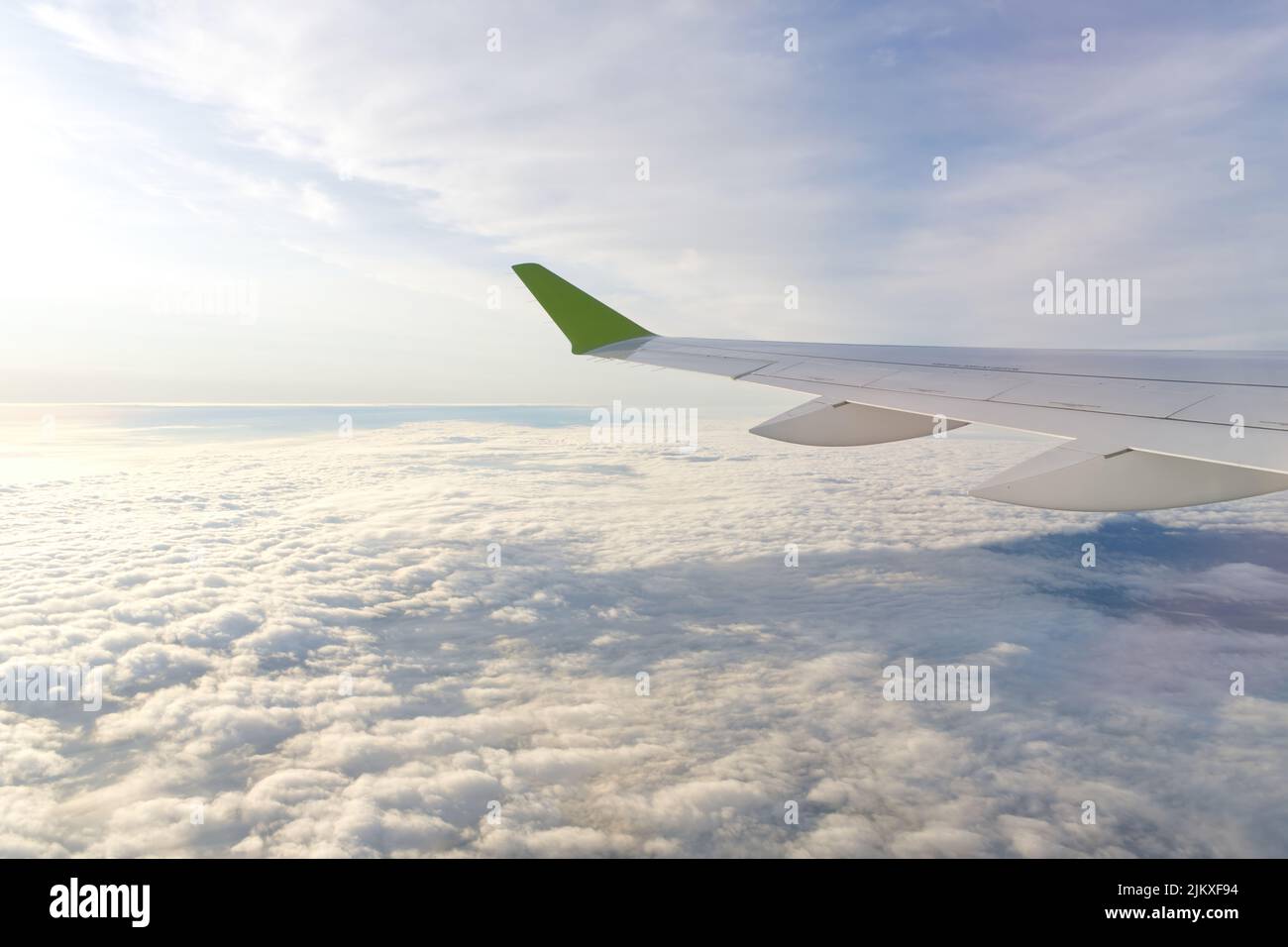 The wing of an airborne aircraft above the clouds. sunny weather and ...