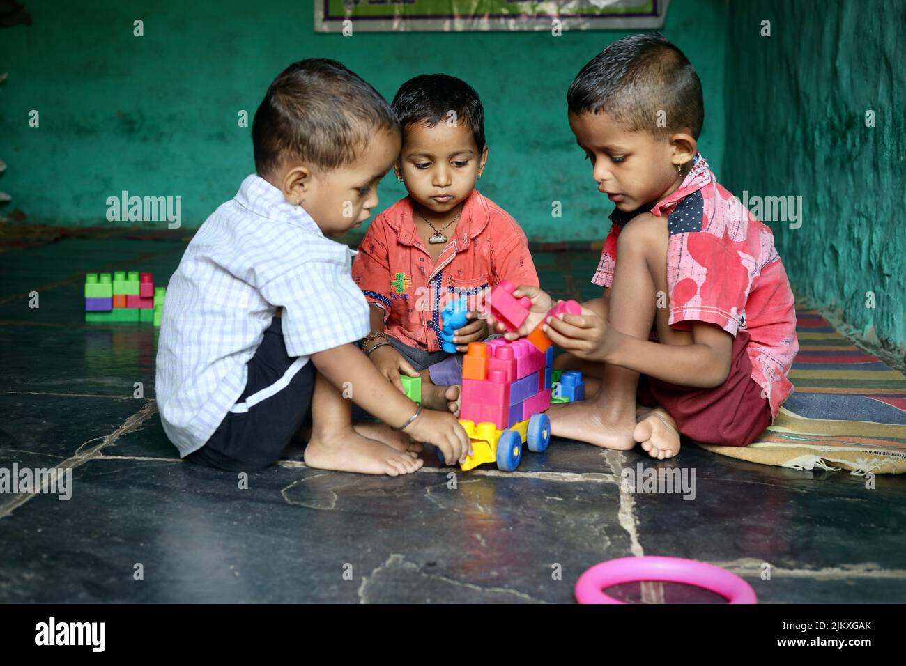 A selective focus of face of a south Indian village kid playing with building blocks in a ...