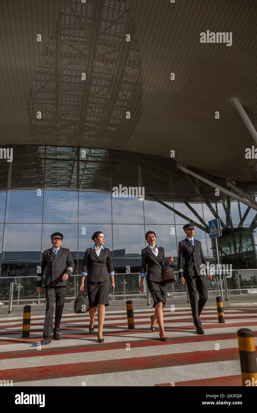 Two flight attendants with bags walking next to the pilots outdoor ...