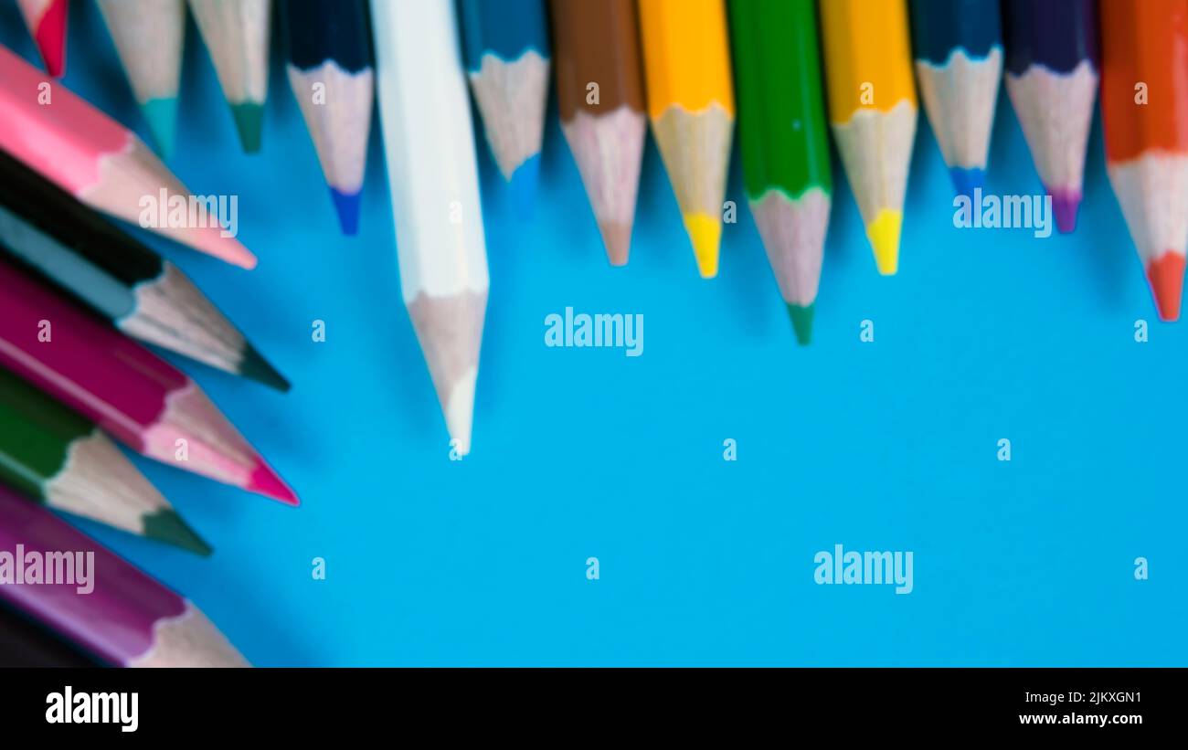 A bunch of color pencil on a blue background. Selective focus on the ...