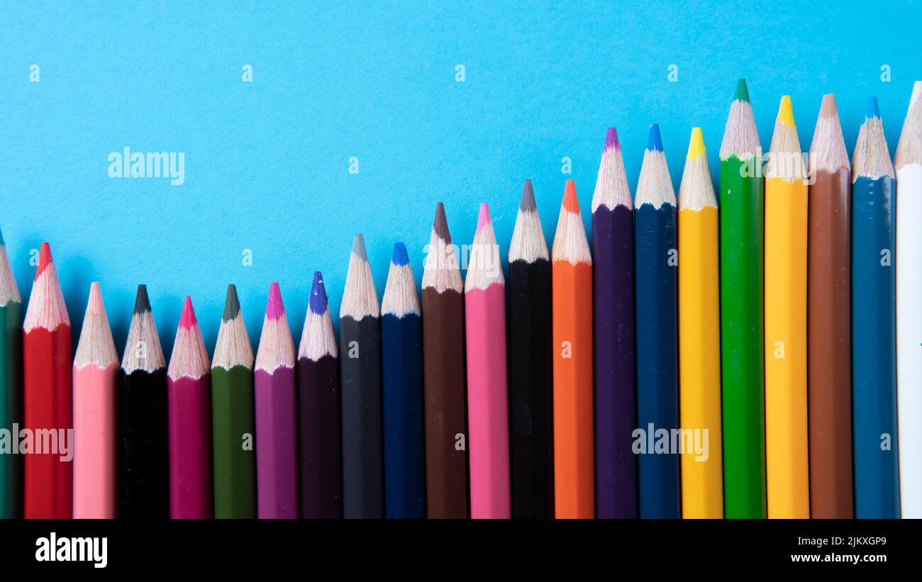 A bunch of color pencil on a blue background. Selective focus on the ...