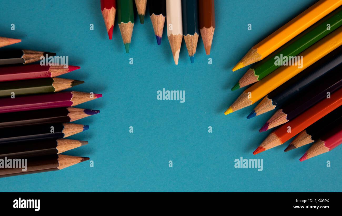 A bunch of color pencil on a blue background. Selective focus on the ...