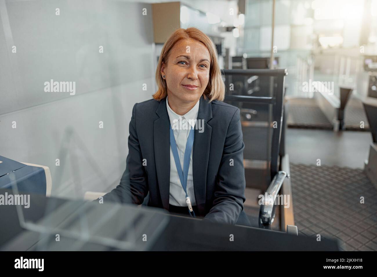 Airport employee sitting at the check-in desk Stock Photo - Alamy