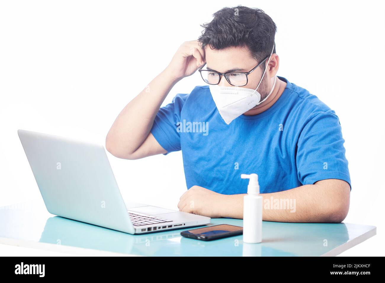 man wearing mask while using laptop and sanitizing hands Stock Photo ...