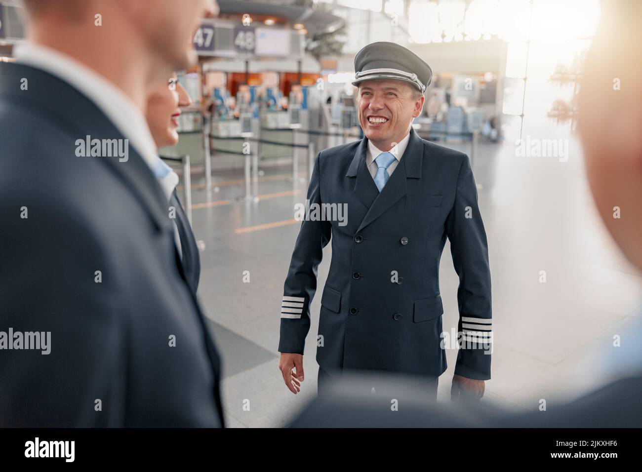 Happy pilot in uniform talking with colleagues at airport Stock Photo ...