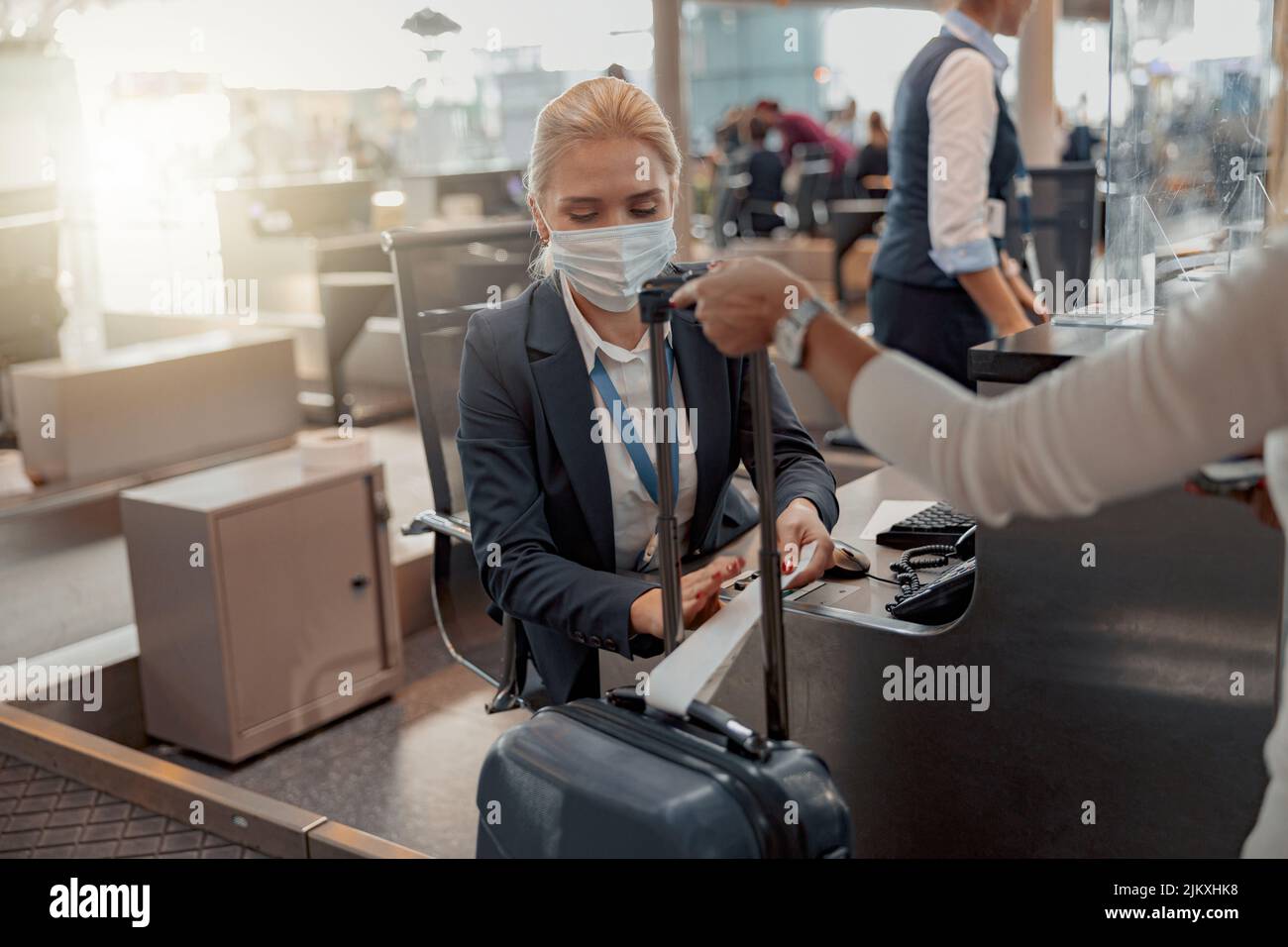 Female traveler putting her luggage on weight at check-in counter at ...