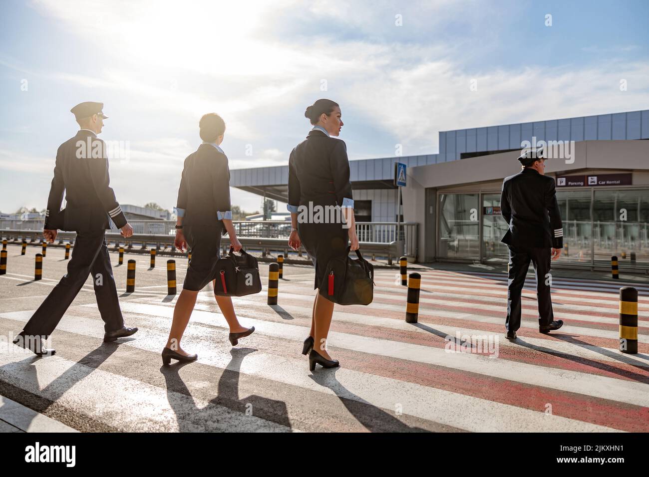 Flight attendants with bags and pilots crossing the road in the airport ...