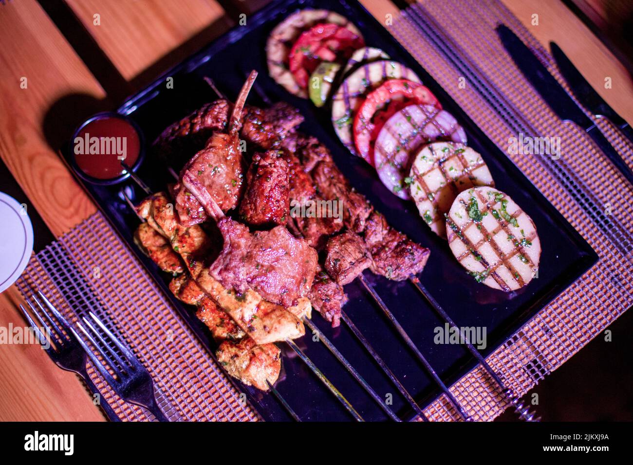 A plate of Chicken and beef BBQ with grilled tomatoes, potatoes and ...