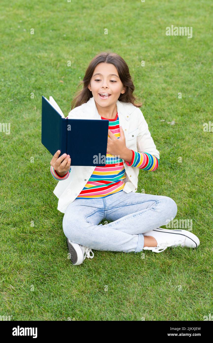 proud teen girl read book sitting on grass. reading book. reader girl ...