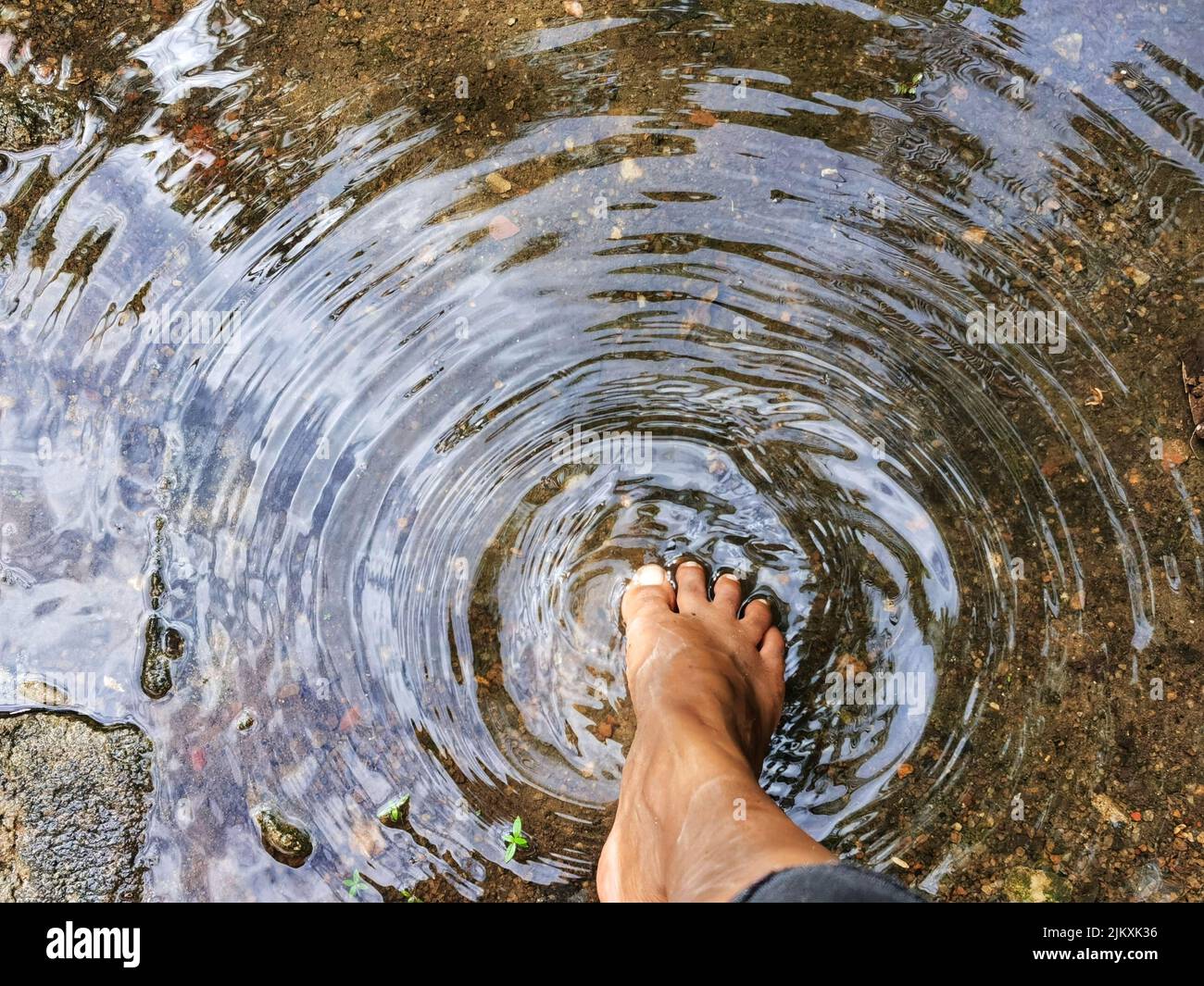 A foot on a water puddle creating a circles pattern Stock Photo - Alamy