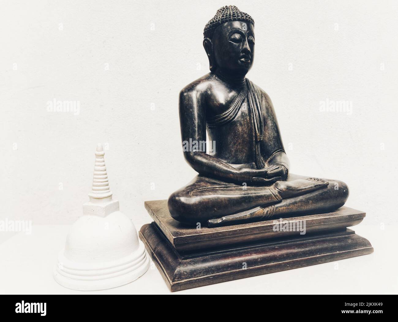A wooden statue of lord buddha and a white color model temple made of ...