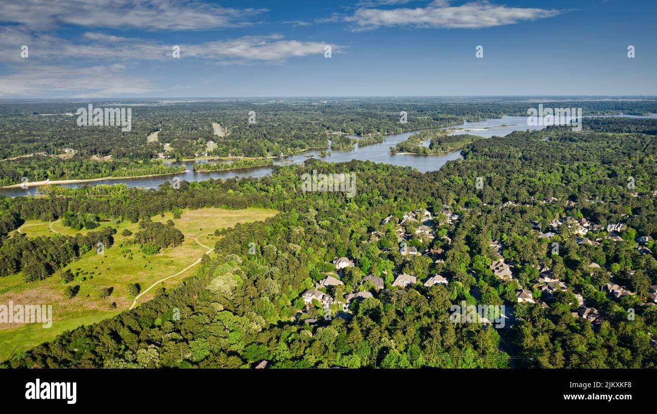 An aerial view of a forest landscape and a lake under a cloudy blue sky ...
