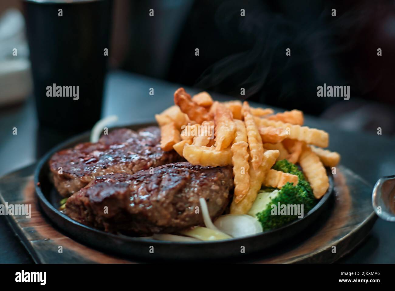 A tasty hot Teppanyaki steak and fries with smoke in black plate Stock ...
