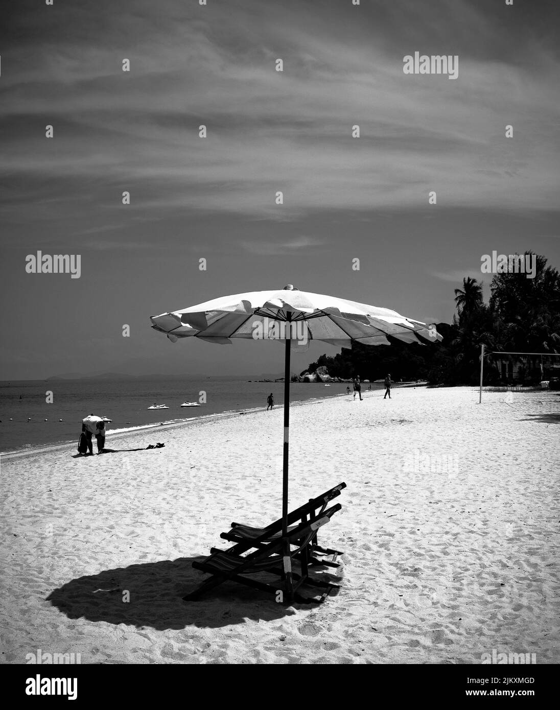 A grayscale shot of a parazol and a sunbed at the beach Stock Photo - Alamy