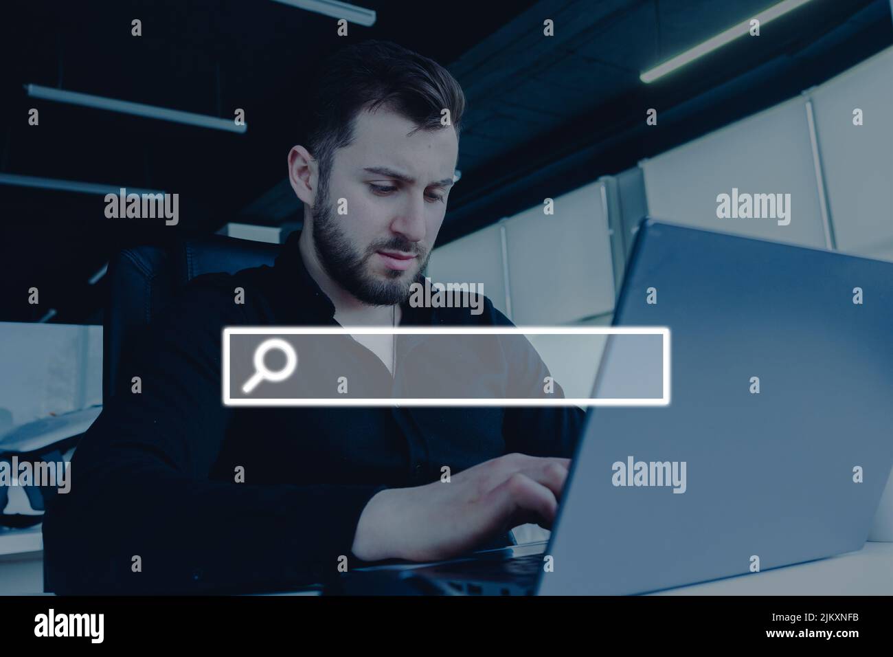 A Young male working on a laptop in the office with a visual screen ...
