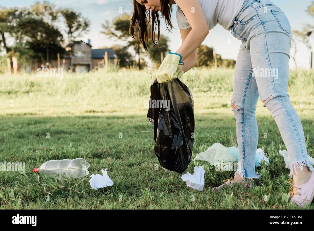 A young Hispanic girl collecting the garbage in a field in Argentina ...