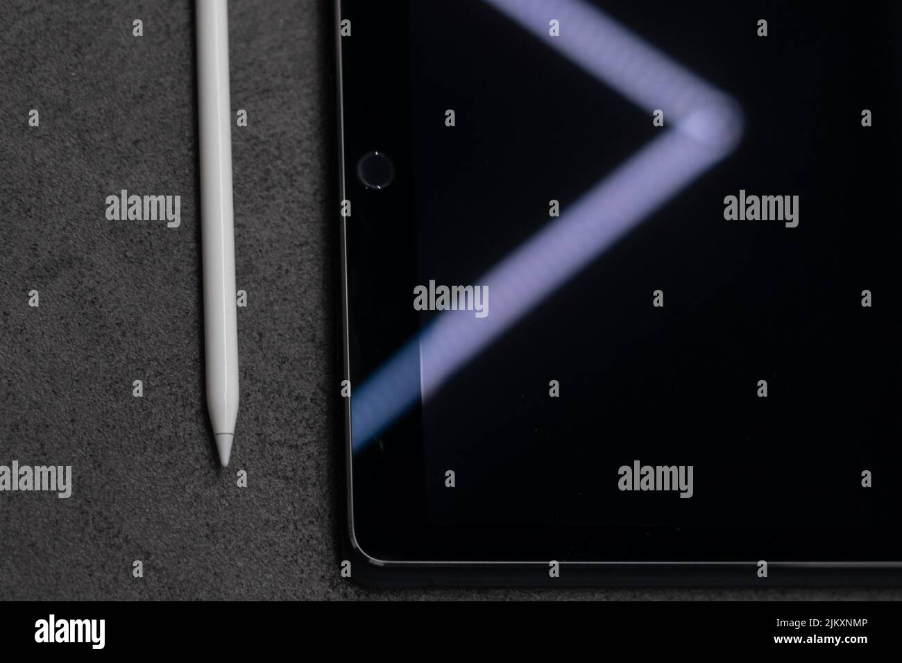 A top view of a black tablet with a white pen on the grey surface Stock ...