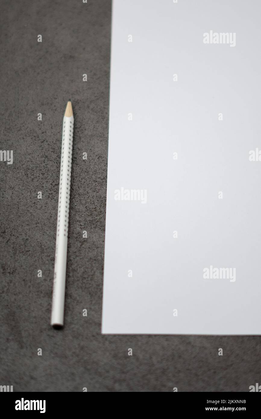 A vertical closeup shot of a piece of white paper and a pen on the gray ...