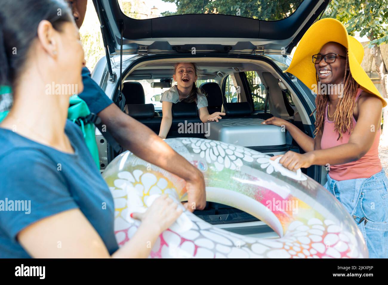 Multiethnic family and friends loading bags in car, preparing baggage ...