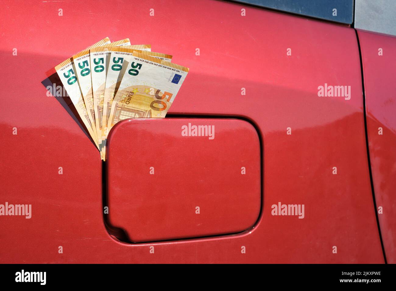 Fifty euro banknotes sticking out of a closed fuel tank, close up of ...