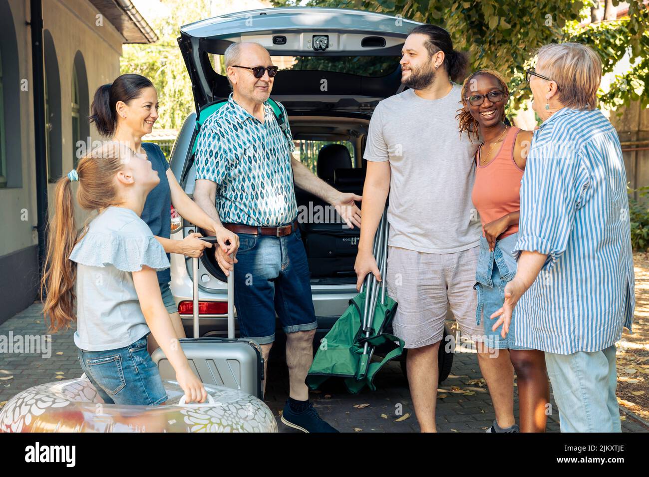 Multiethnic people loading bags in vehicle trunk, travelling on holiday ...