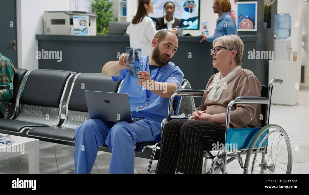 Paralyzed woman and nurse analyzing radiography scan in waiting room ...