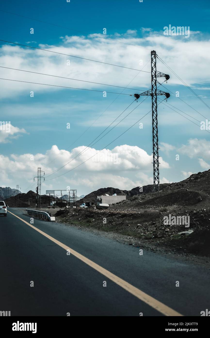 A beautiful shot of an asphalt road, electrical cables, and mountains ...