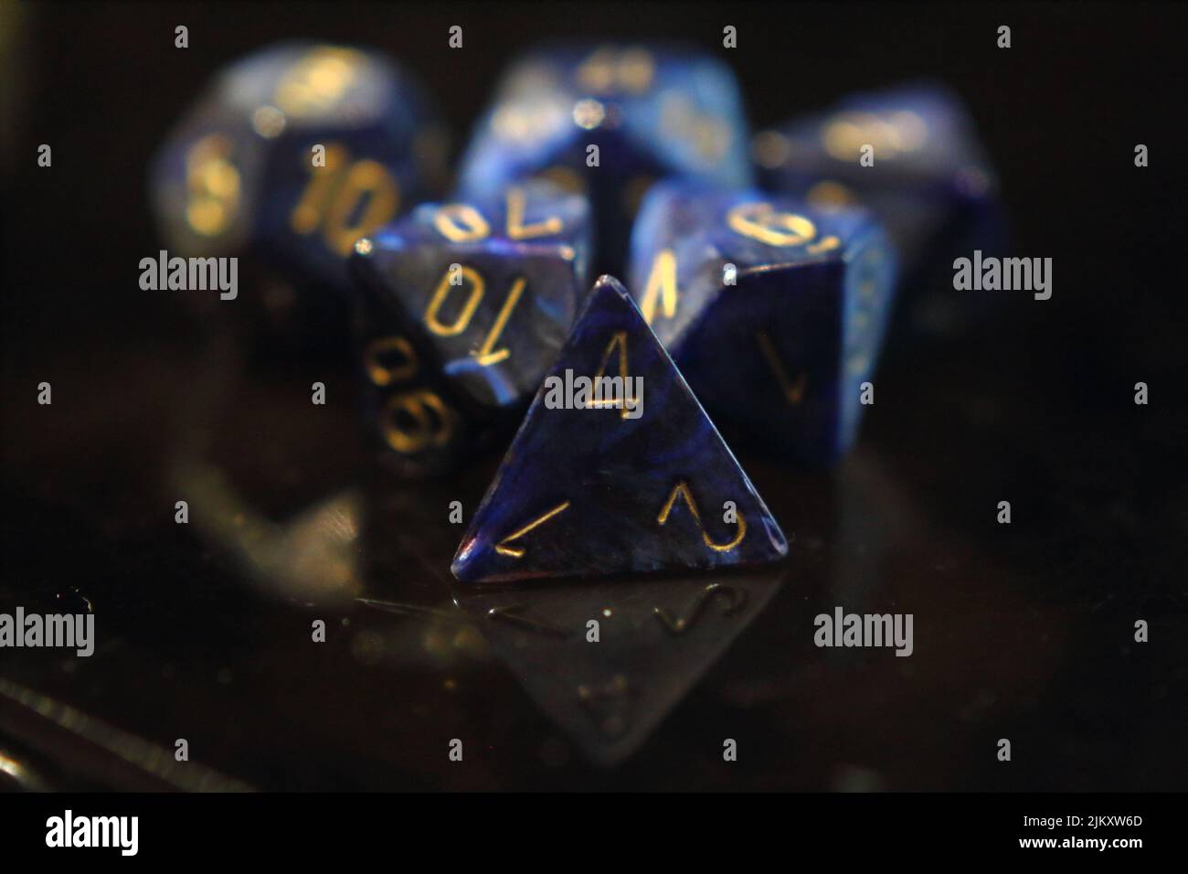 Blue metallic swirled dice with gold numbers on the reflective surface ...
