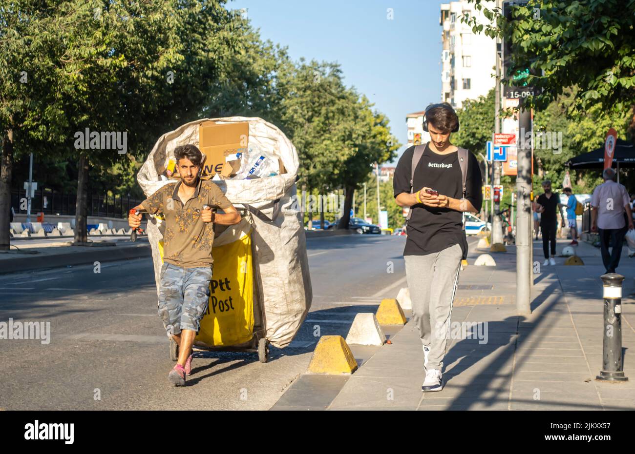 Informal recycling teenager worker dragging large hand-pulled cart ...