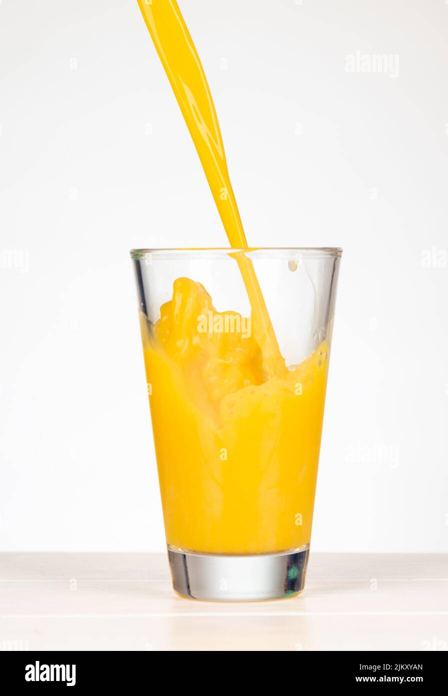 pour orange juice in a glass with splashing Stock Photo - Alamy