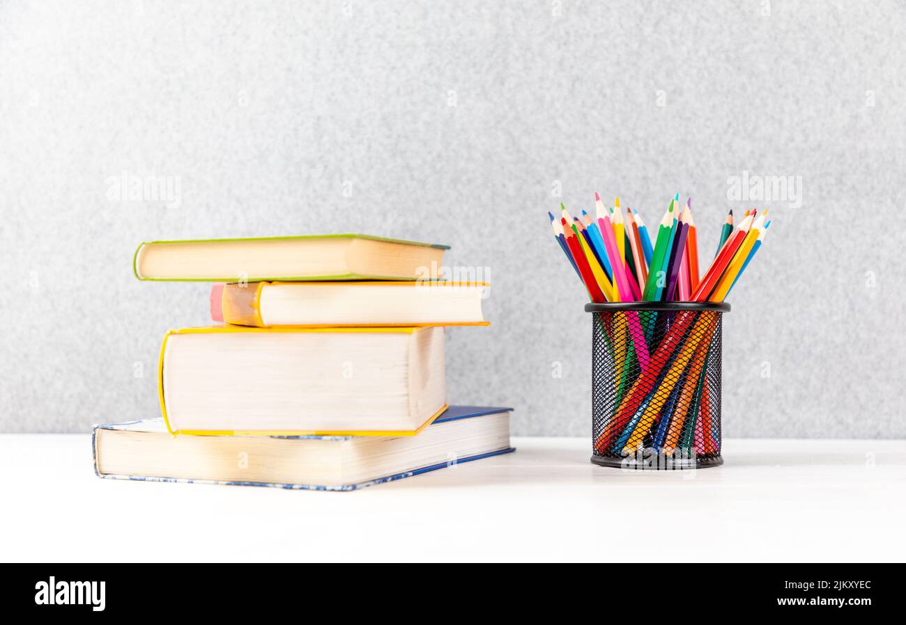 colorful pens on a desk with books with a gray background and copyspace ...