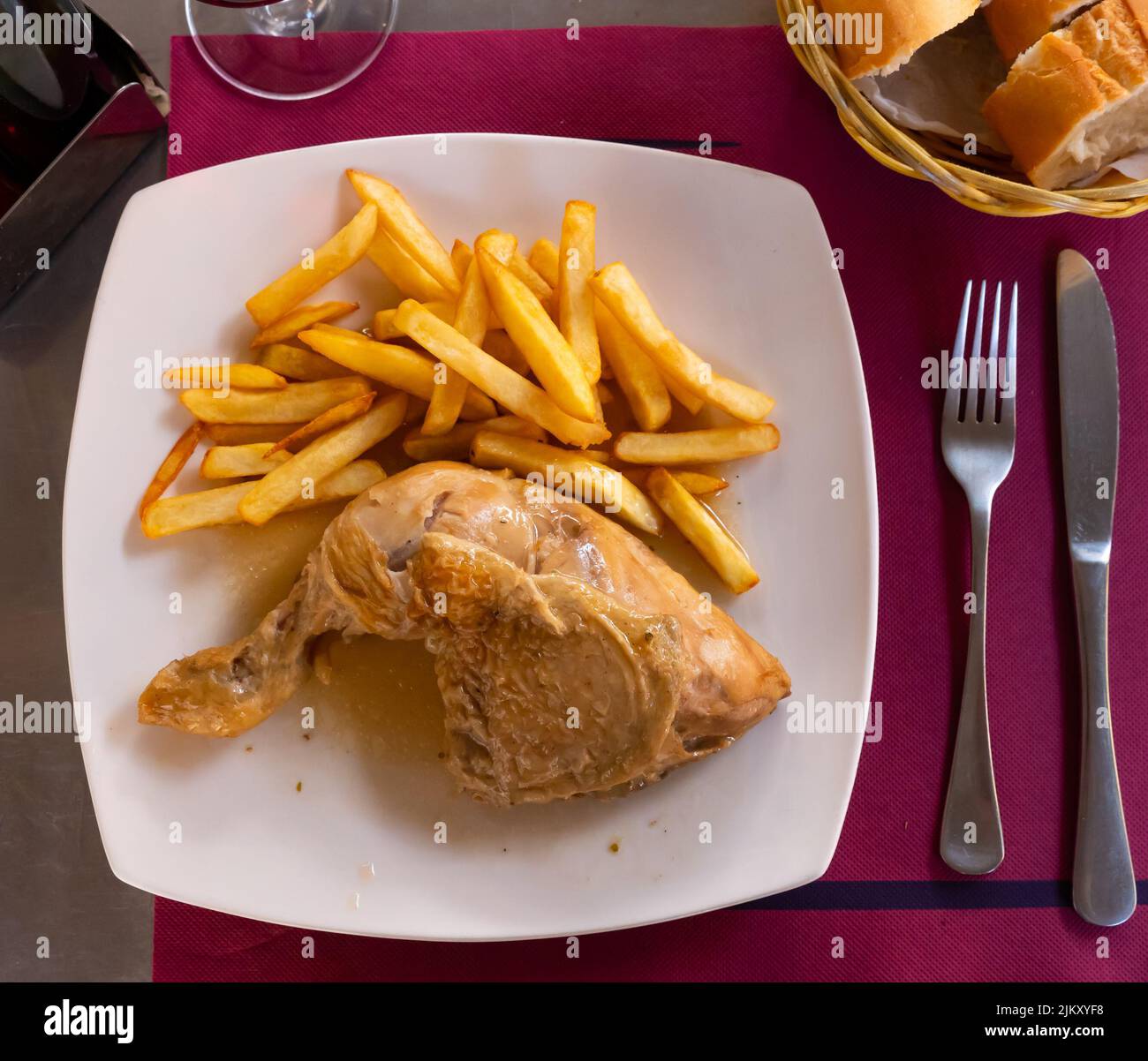 Baked chicken leg served on plate with side dish of fried potatoes ...