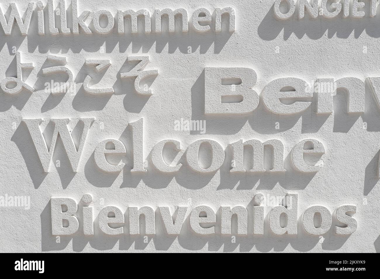 word welcome written in several languages on a white wall Stock Photo ...
