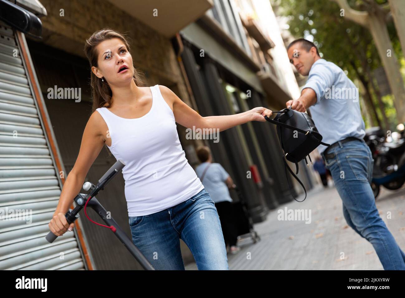 Robbery pulling backpack from woman with scooter Stock Photo - Alamy