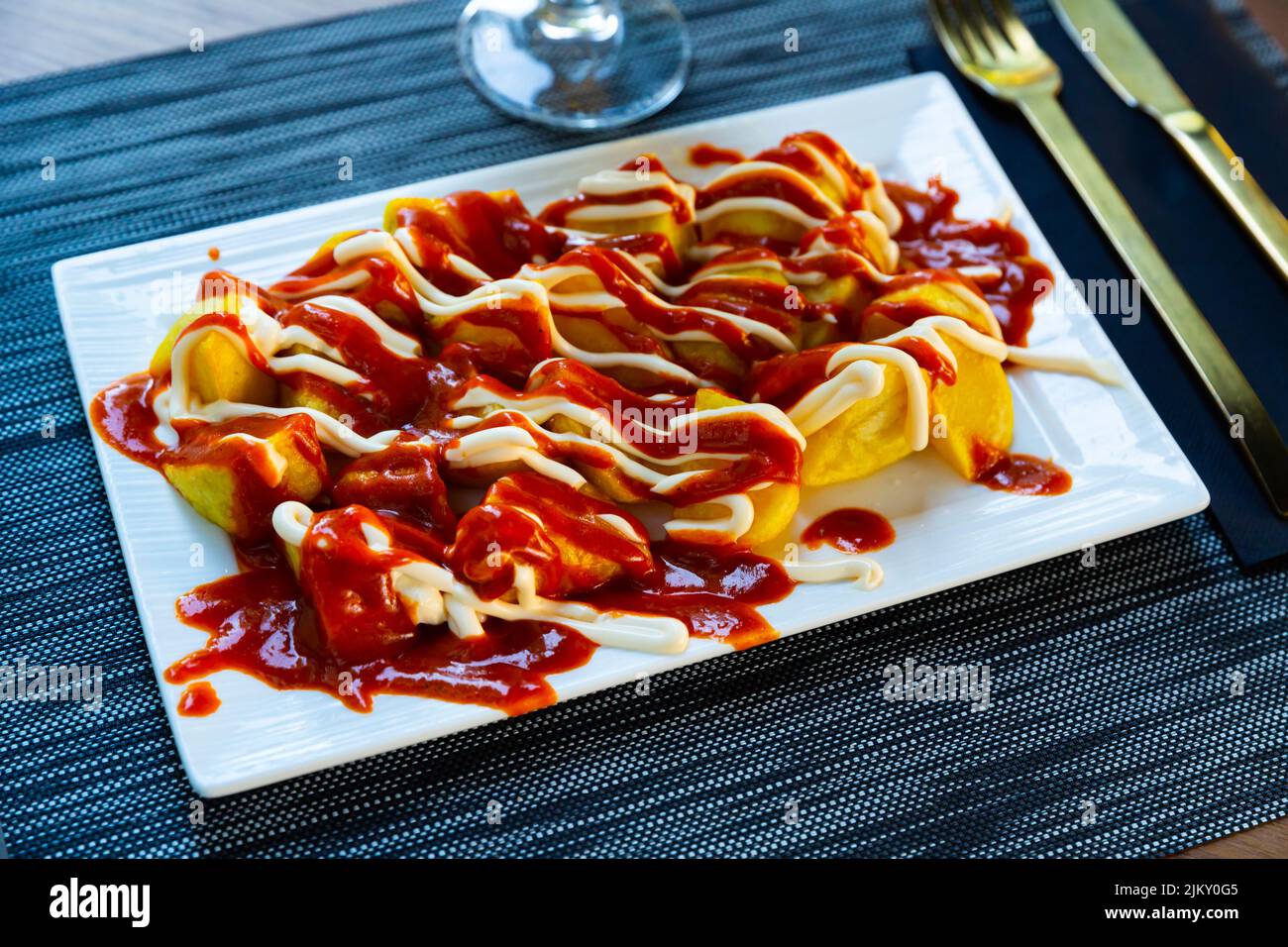Prepared patatas bravas with sauce served on plate on wooden table ...